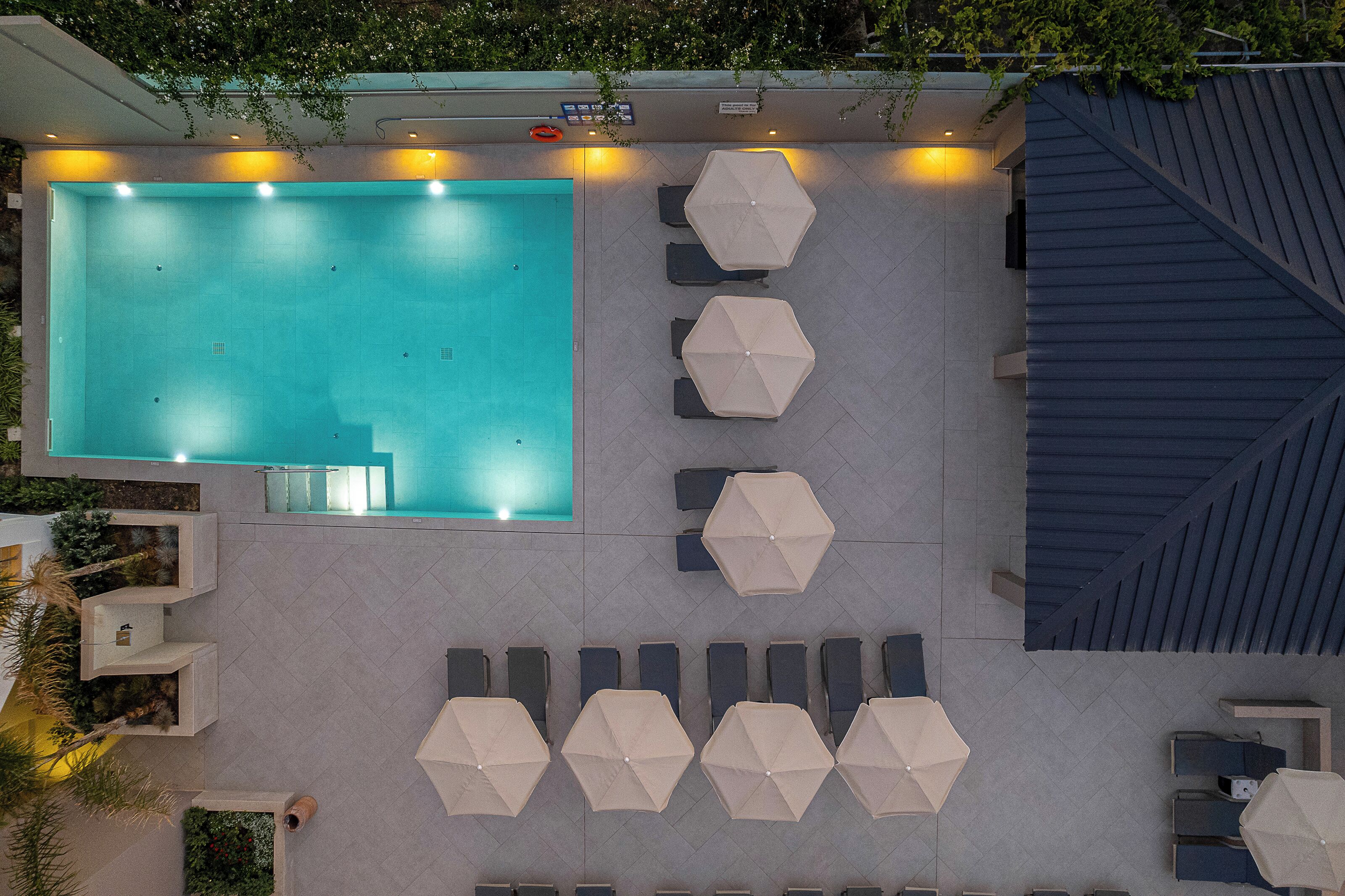 Vista aérea de uma área de piscina com assentos hexagonais e um espaço coberto para relaxar.