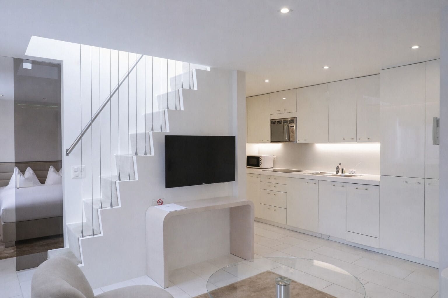 Cozinha moderna com armários brancos, uma TV de tela plana na parede e uma escada com design exclusivo.