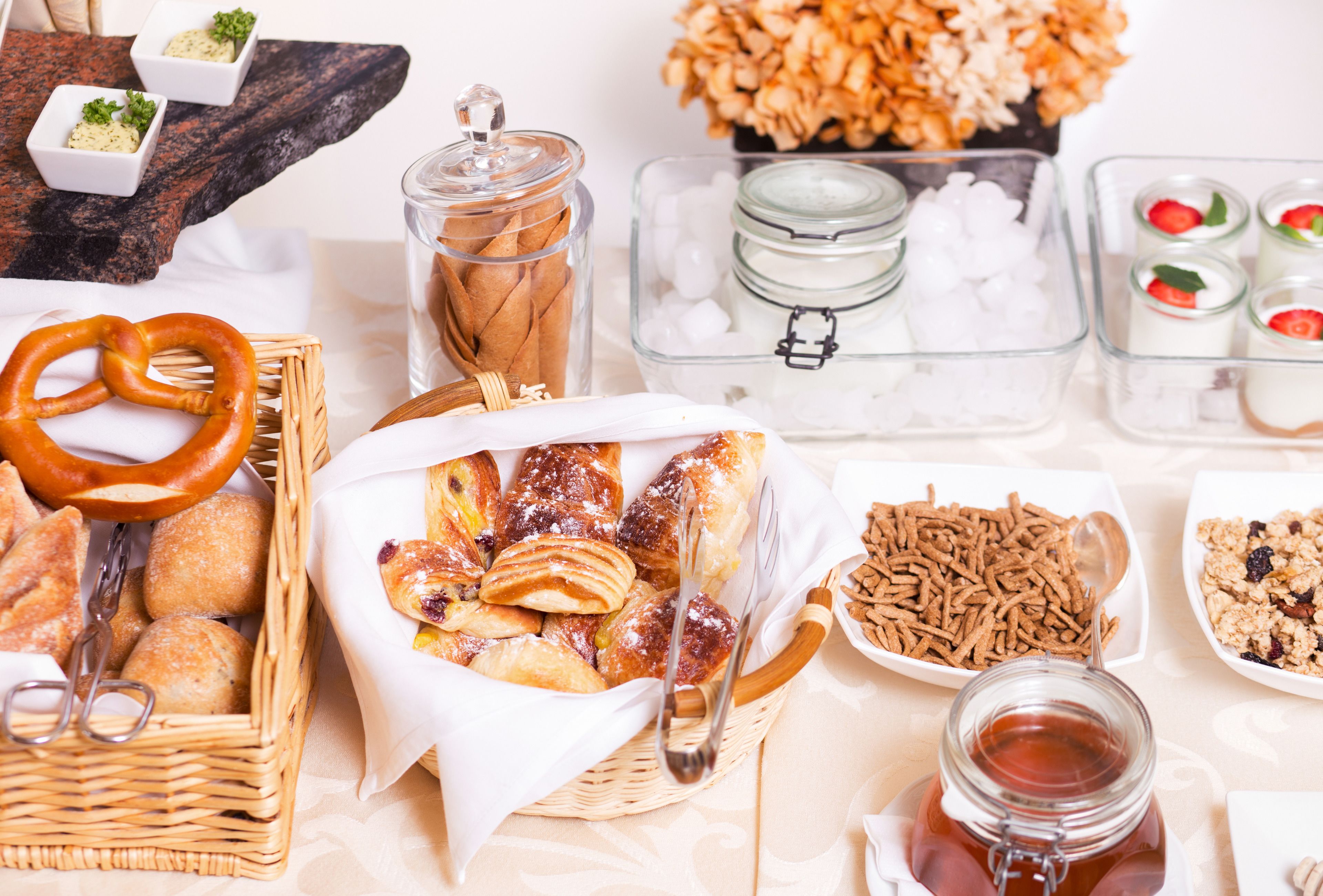 Uma mesa com diversos alimentos, incluindo pretzels, doces e potes de mel.