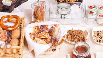 Uma mesa com diversos alimentos, incluindo pretzels, doces e potes de mel.