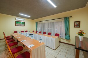 Uma sala de conferências com uma mesa comprida, cadeiras e um bebedouro.