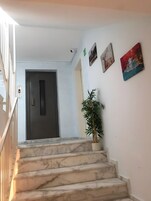 Uma escadaria com degraus de mármore que levam a uma porta com visor digital exibindo o número 6.