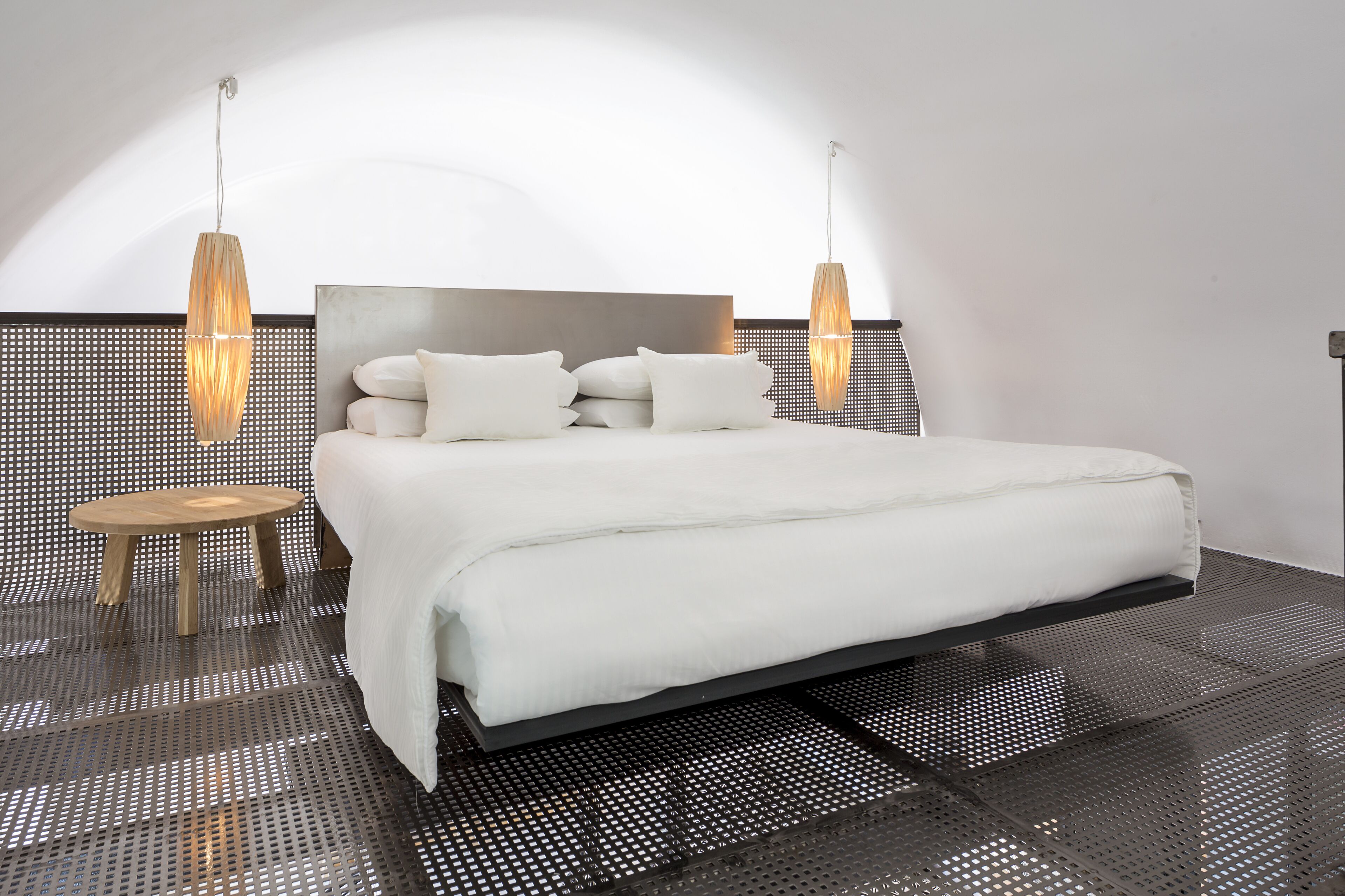 Quarto moderno com uma cama grande, duas mesas de cabeceira e uma mesa redonda.