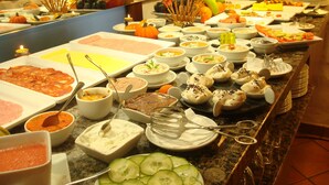 Um buffet com diversos alimentos e utensílios.