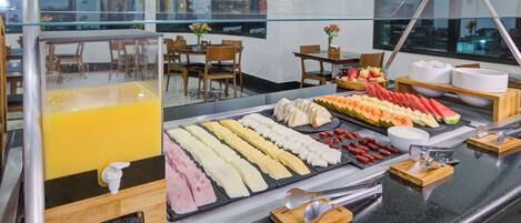 Buffet com diversos alimentos e um dispensador de suco.