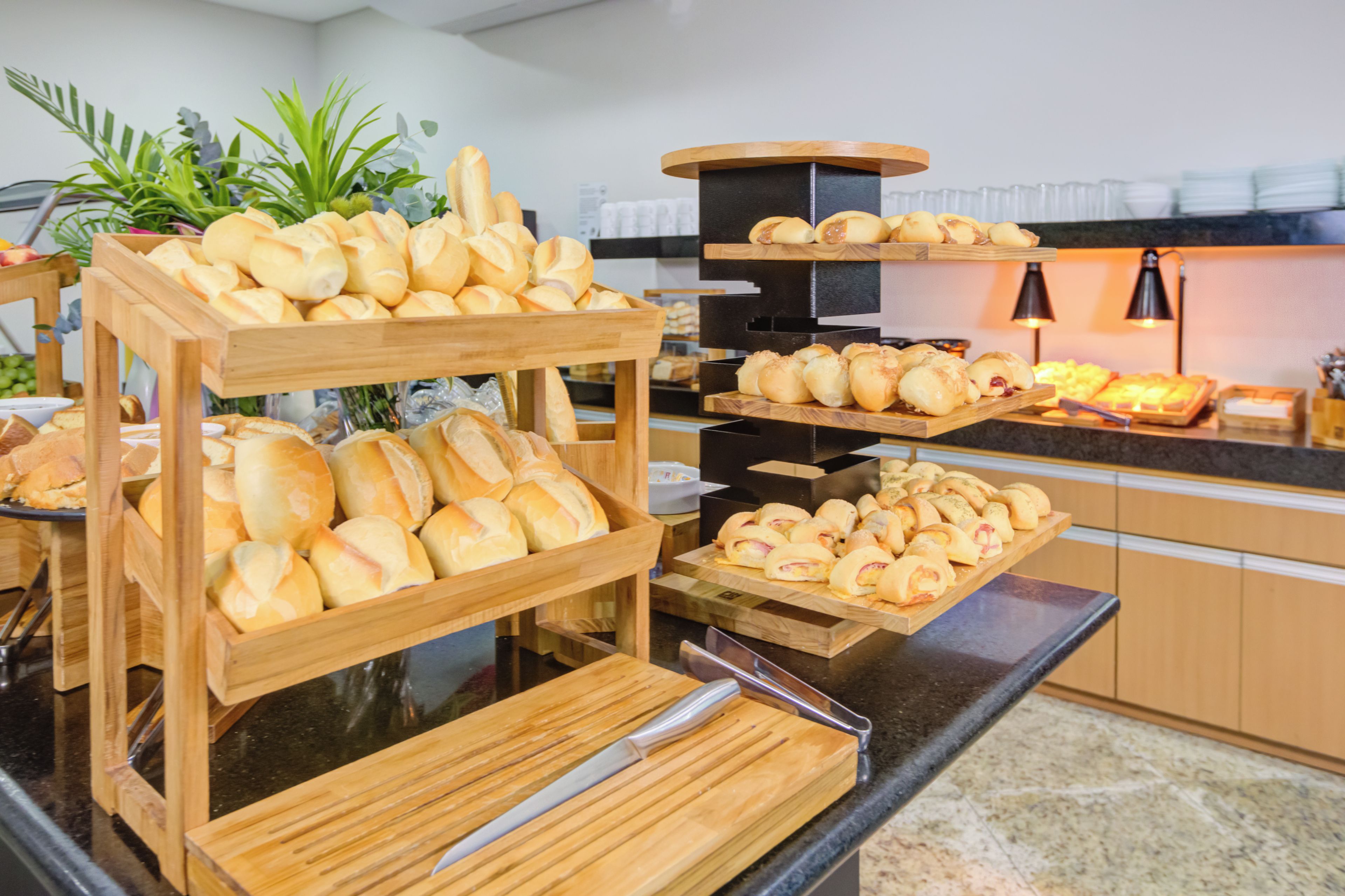 Buffet com diversos produtos de pastelaria expostos em suportes de madeira.