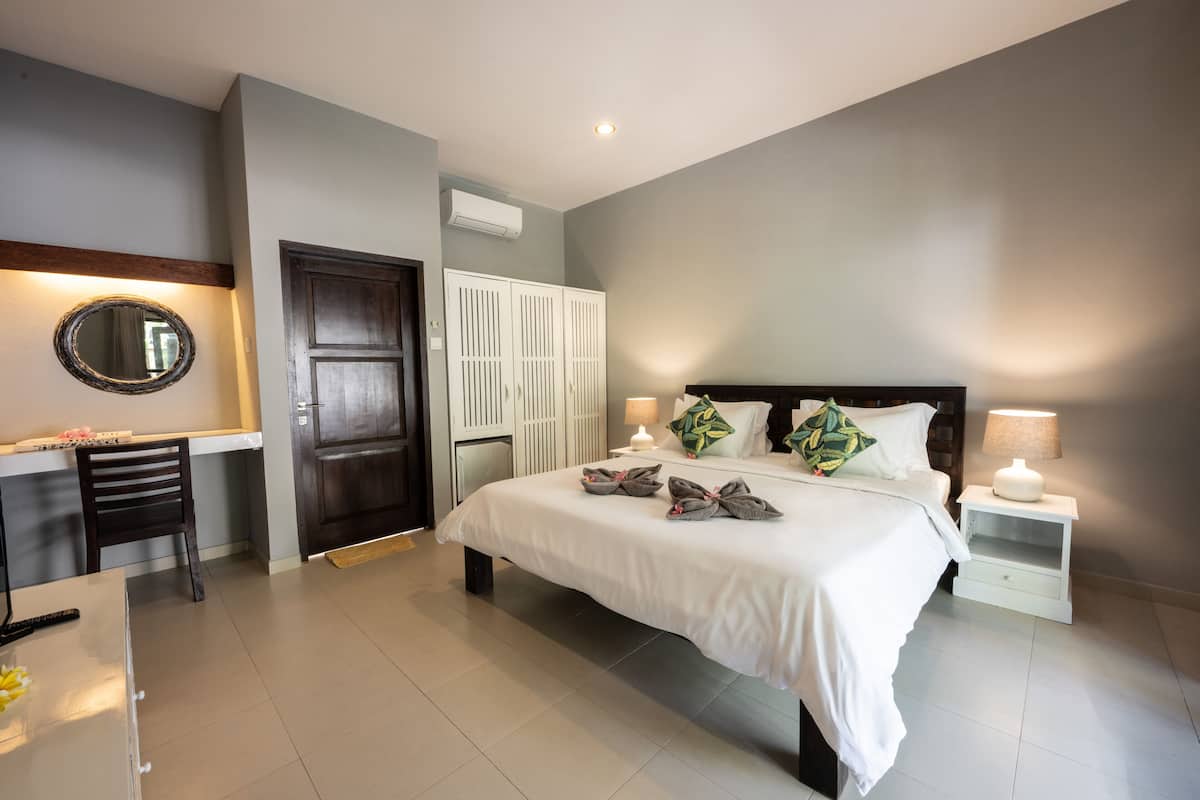 Quarto bem organizado com cama, mesas de cabeceira, escrivaninha e guarda-roupa.