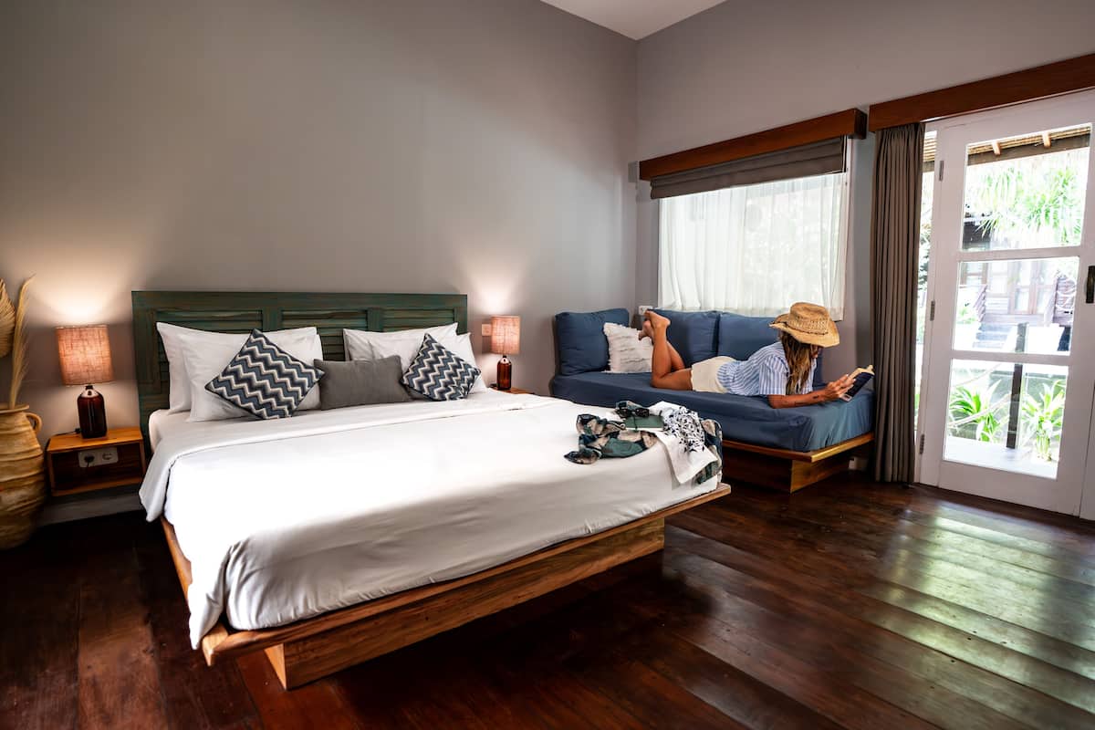 Um quarto com uma cama, um sofá e uma janela com cortinas.