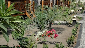 Resort com chalés de telhado de palha, palmeiras e um calçadão.