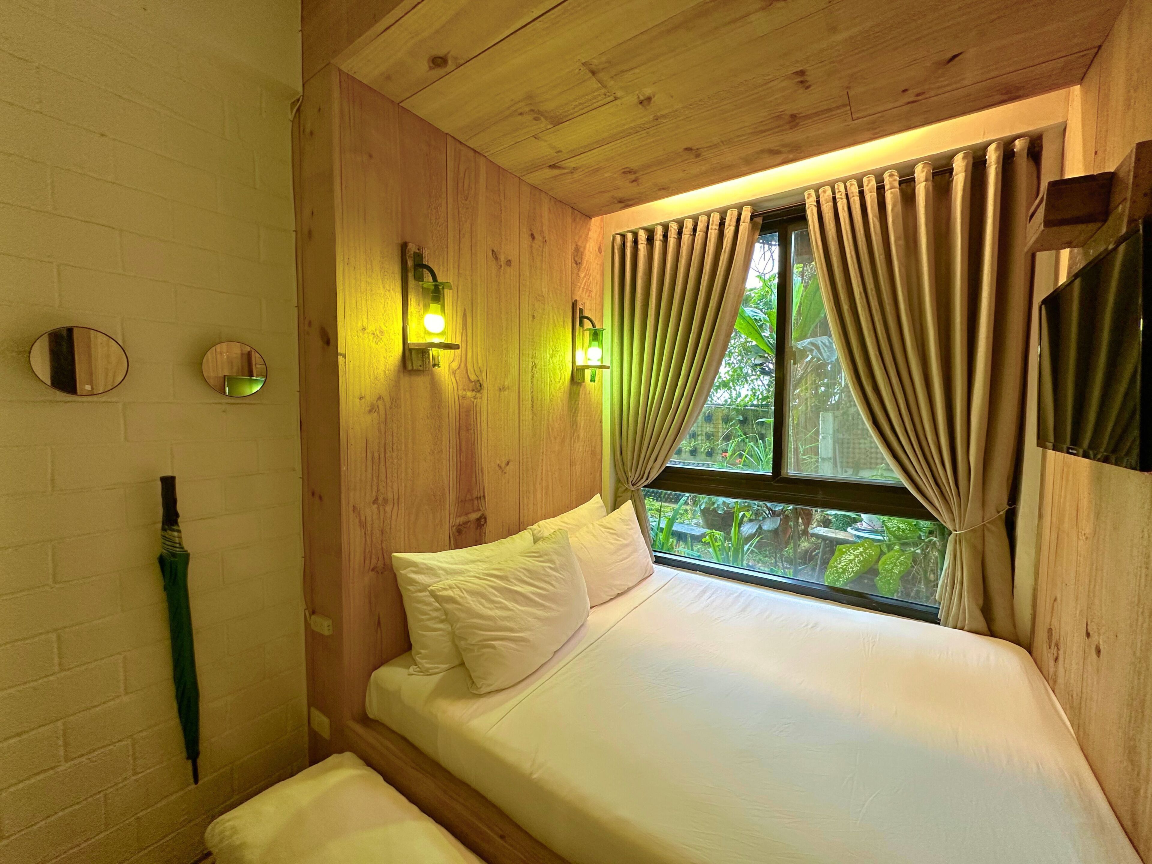 Quarto com painéis de madeira, uma cama, um espelho e uma janela com cortinas.