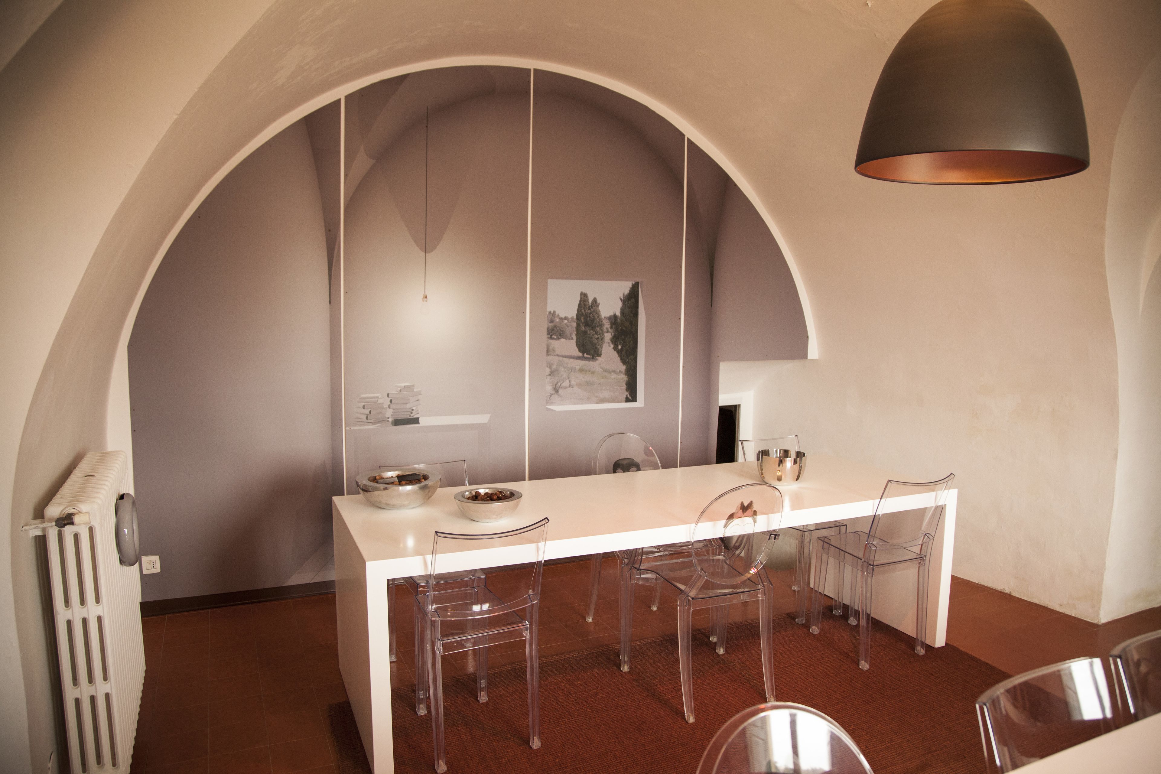 Uma área de refeições moderna com uma mesa branca, cadeiras transparentes e um teto em arco grande.