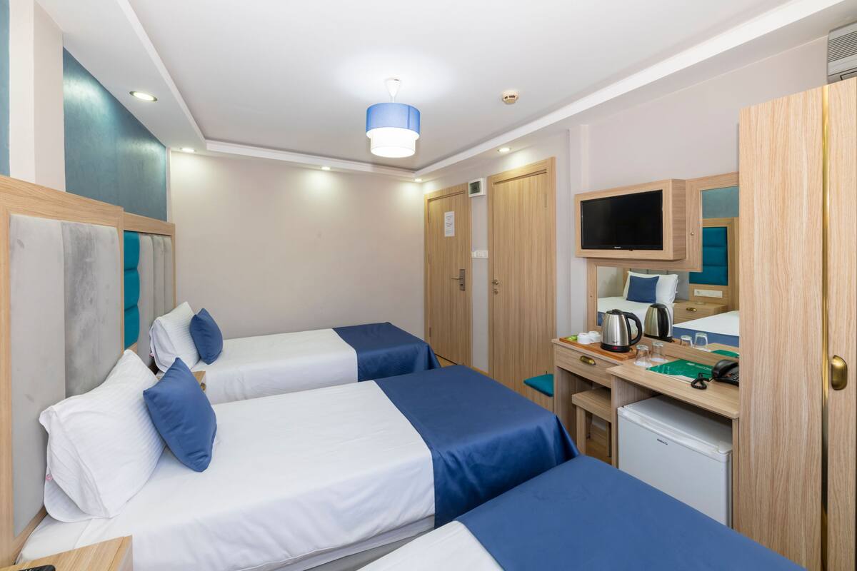 Quarto de hotel com duas camas, uma escrivaninha com televisão, mini-frigorífico e micro-ondas.