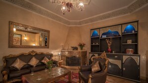 Uma sala de estar tradicional com lareira, móveis ornamentados e um espelho decorativo.