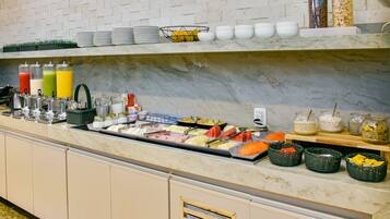Buffet com diversos alimentos e bebidas, incluindo sumos e cereais.