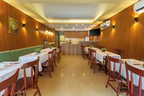 Um restaurante com painéis de madeira, várias mesas e cadeiras.