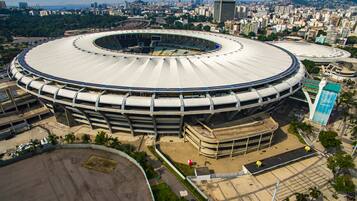 Um estádio amplo com design circular, rodeado por edifícios urbanos e áreas verdes.