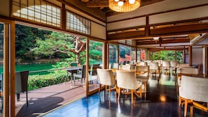 Um quarto espaçoso com vista para um lago, vigas de madeira e uma luminária tradicional em estilo japonês.