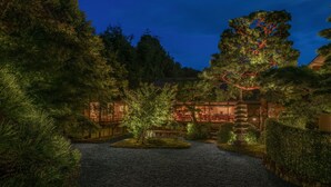 Um jardim japonês tradicional com lago de carpas, lanternas de pedra e um edifício em estilo pagoda.