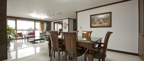 Uma sala de jantar com mesa e cadeiras, um sofá e um vaso de planta.