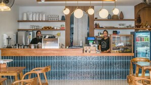 Um café com móveis de madeira, um painel de azulejos e uma vitrine com lanches.