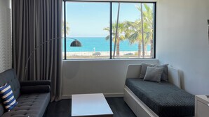 Quarto moderno com vista para o mar, um sofá, uma mesa pequena e uma cadeira.