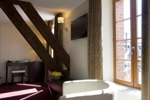 Quarto com escada de madeira, uma escrivaninha com cadeira, televisão e janela com cortinas.