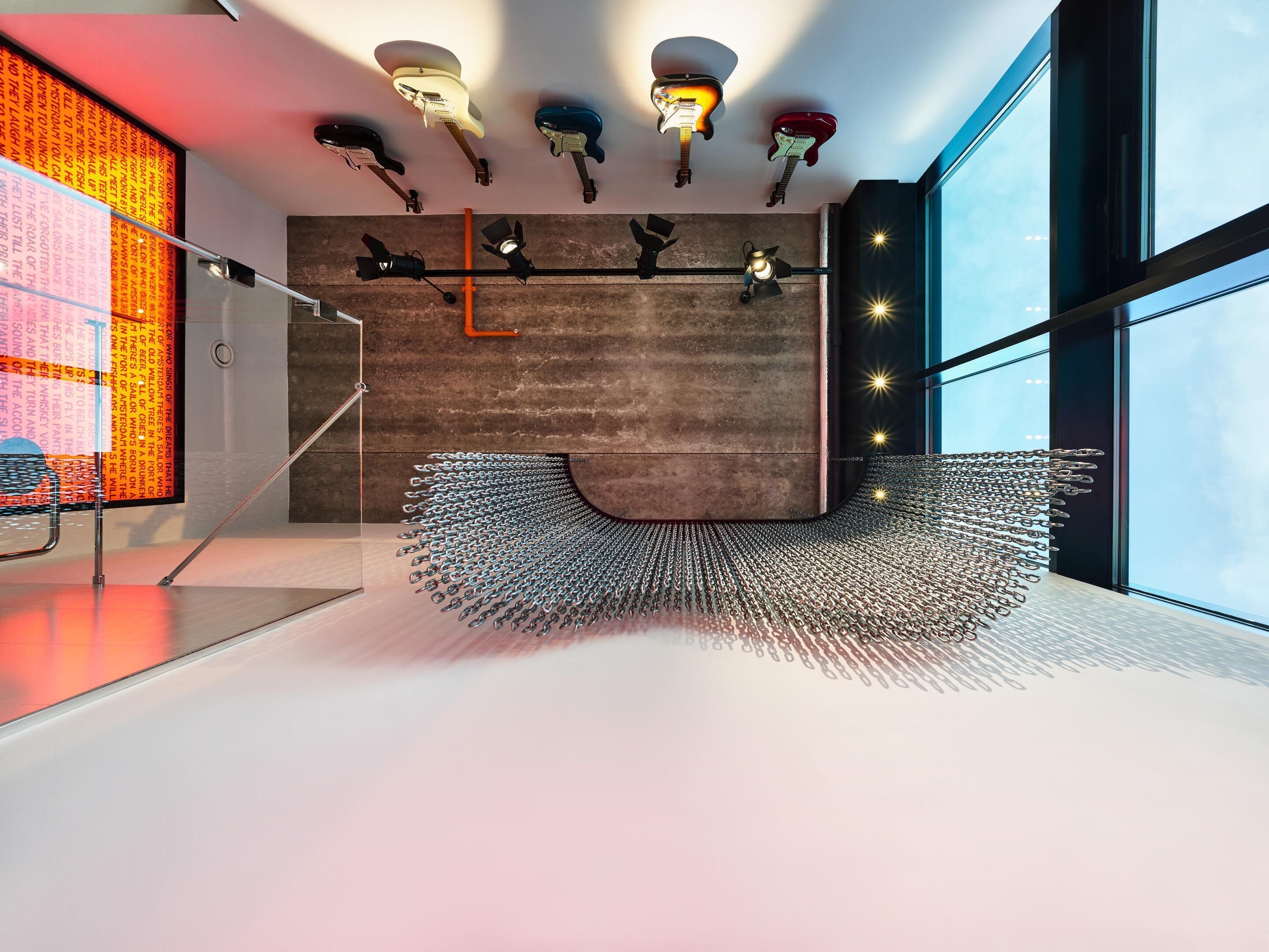 Um interior moderno com uma janela ampla, um painel de guitarras penduradas na parede e uma instalação de corrente original.