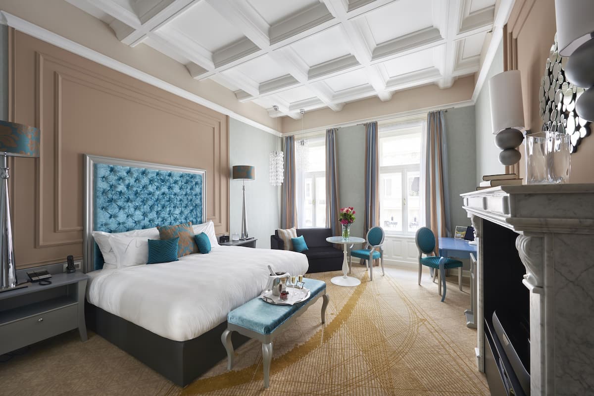 Quarto de hotel com cama grande, escrivaninha, cadeira e lareira.
