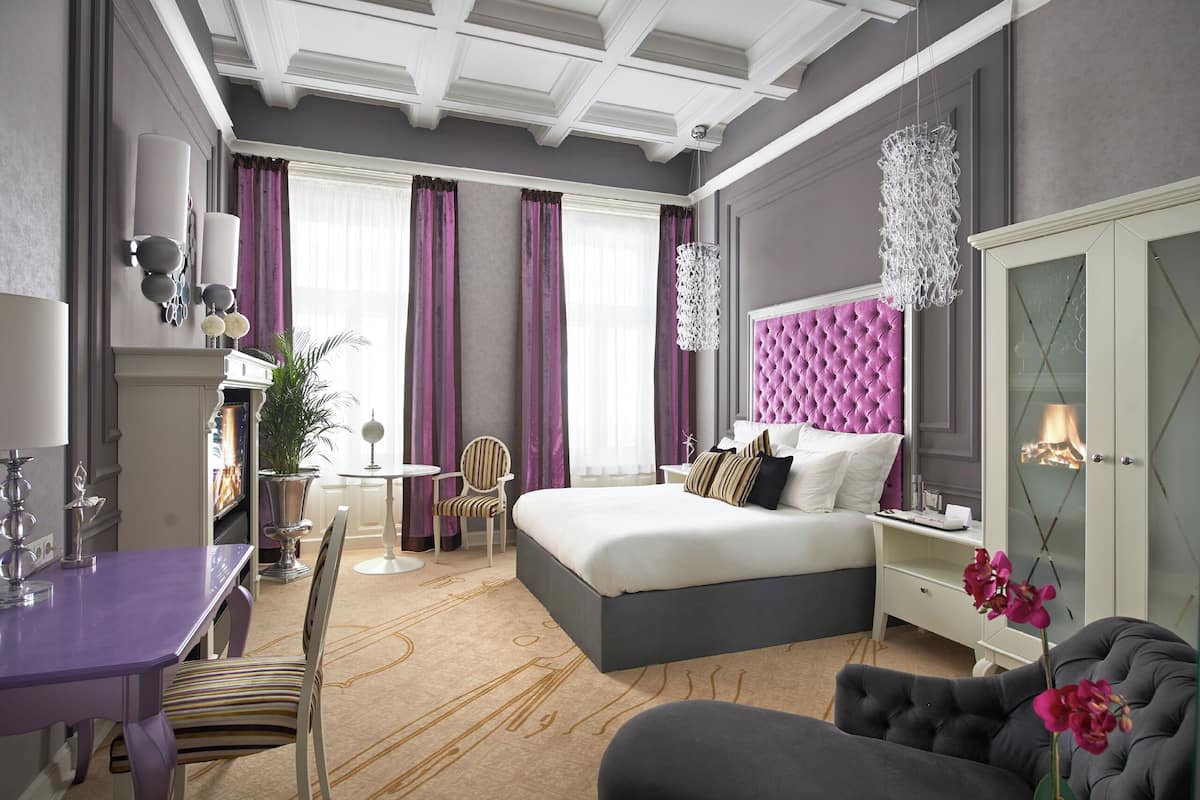 Quarto de hotel moderno com uma cama grande, área de jantar e espaço para sentar.