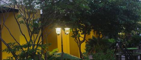 Um edifício amarelo com um pátio, rodeado por árvores e plantas.