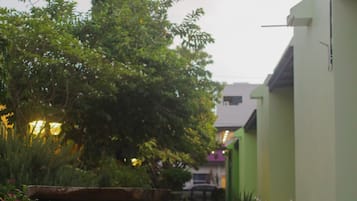 Uma passagem de concreto estreita, ladeada por edifícios verdes e árvores.