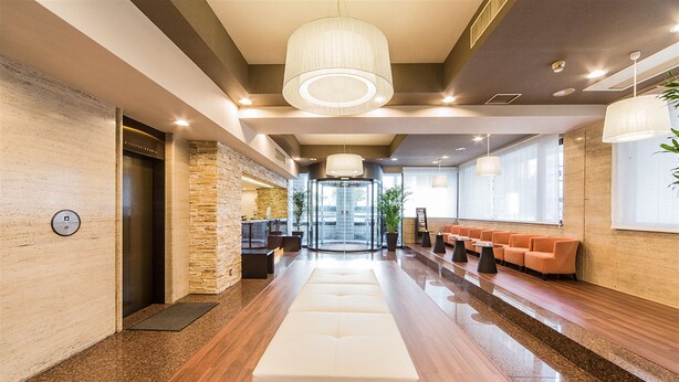 Um lobby moderno com um balcão de recepção extenso, área de estar e porta giratória.
