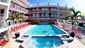 Hotel com vários andares, piscina central, área de estar ao ar livre e palmeiras.