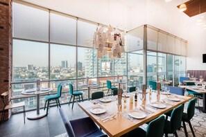 Restaurante com grandes janelas, vista para a cidade e design de interiores moderno.