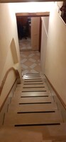 Escada com corrimão e piso ladrilhado que dá acesso a um quarto.