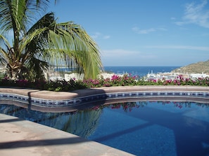 Piscina com vista para o mar e edifícios ao fundo.