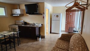 Cozinha compacta com área de jantar, sofá e televisão.