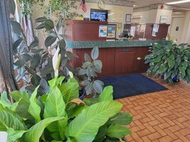 Uma área de recepção com balcão de madeira, televisão e diversos cartazes informativos.