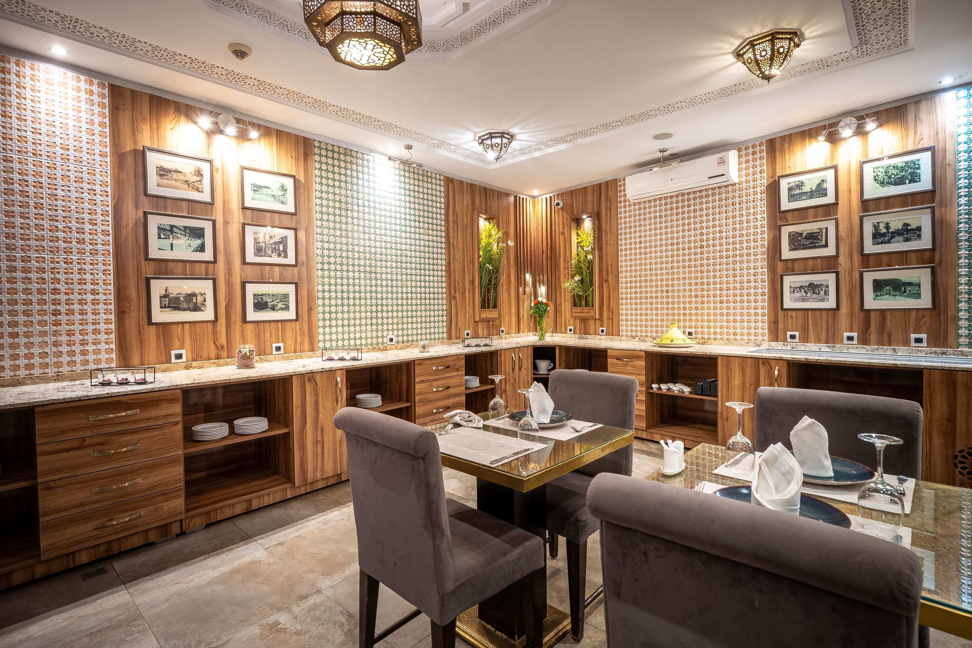 Uma área de refeições com uma mesa de madeira comprida, cadeiras estofadas e quadros nas paredes.