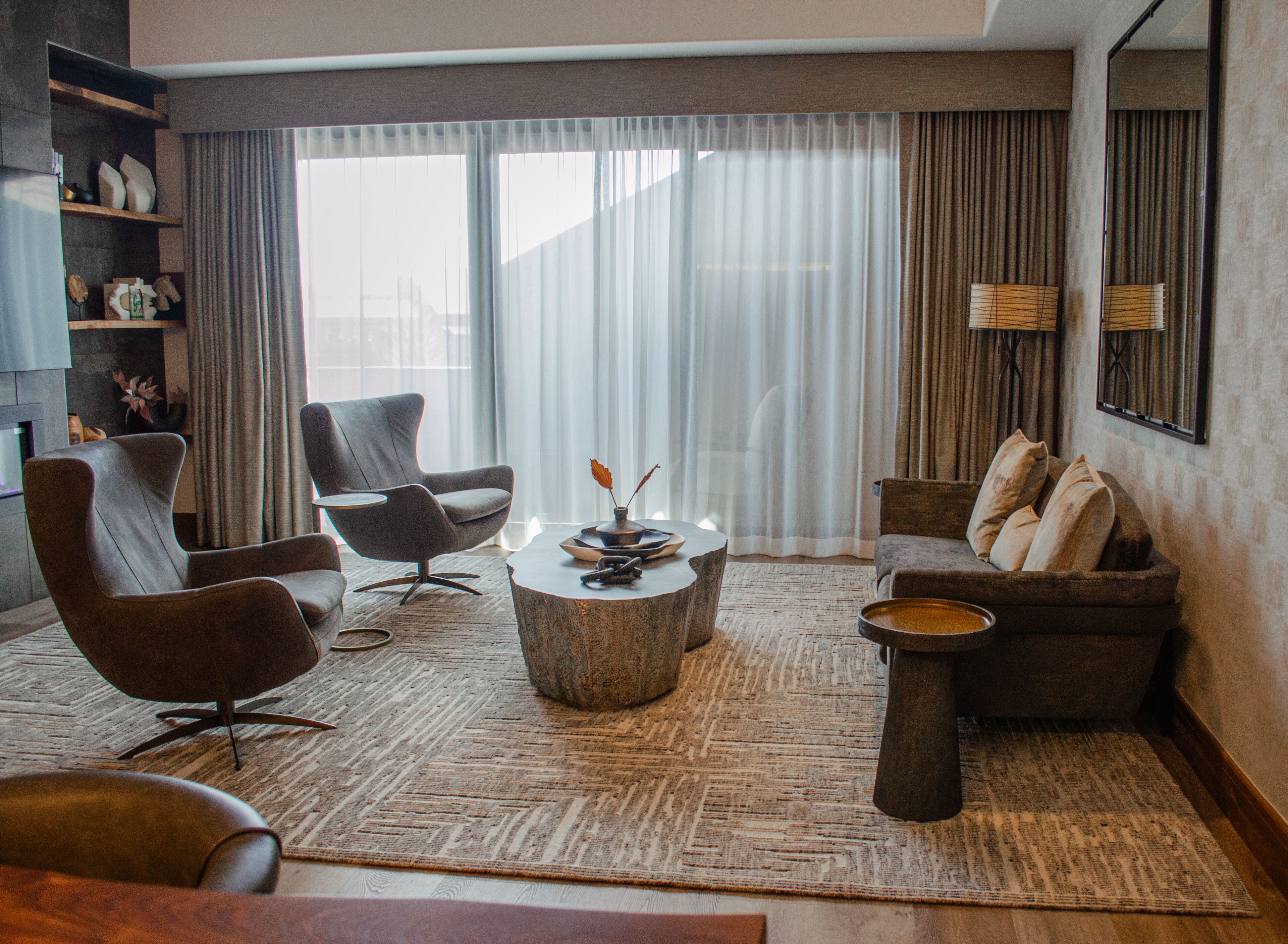 Uma sala de estar moderna com um sofá, poltronas, uma mesa de centro e uma estante.
