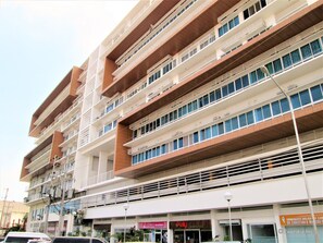 Um edifício de vários andares com varandas, um restaurante Burger & Pizza e uma placa com o nome Dr. Christian V. Manco.