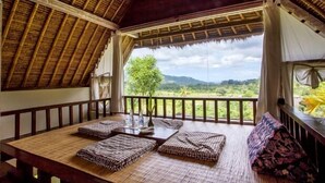 Quarto com mesa de madeira, assentos acolchoados e vista para uma paisagem exuberante.