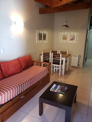 Uma sala de estar aconchegante com um sofá, uma mesa de jantar com cadeiras e uma mesa de centro.