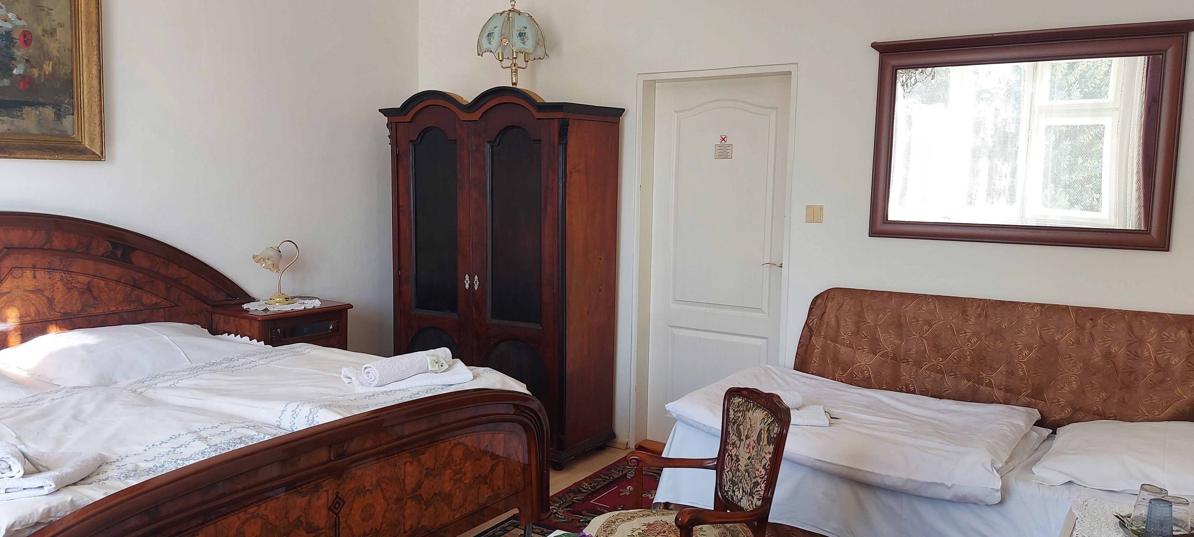 Quarto com duas camas de madeira, um guarda-roupa, uma cadeira e uma janela.