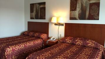 Quarto de hotel com duas camas, uma mesa de cabeceira com telefone e luminárias fixadas na parede.