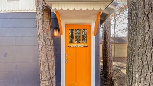 Uma porta laranja vibrante com uma placa que diz 'Wanderoo Cabin'.