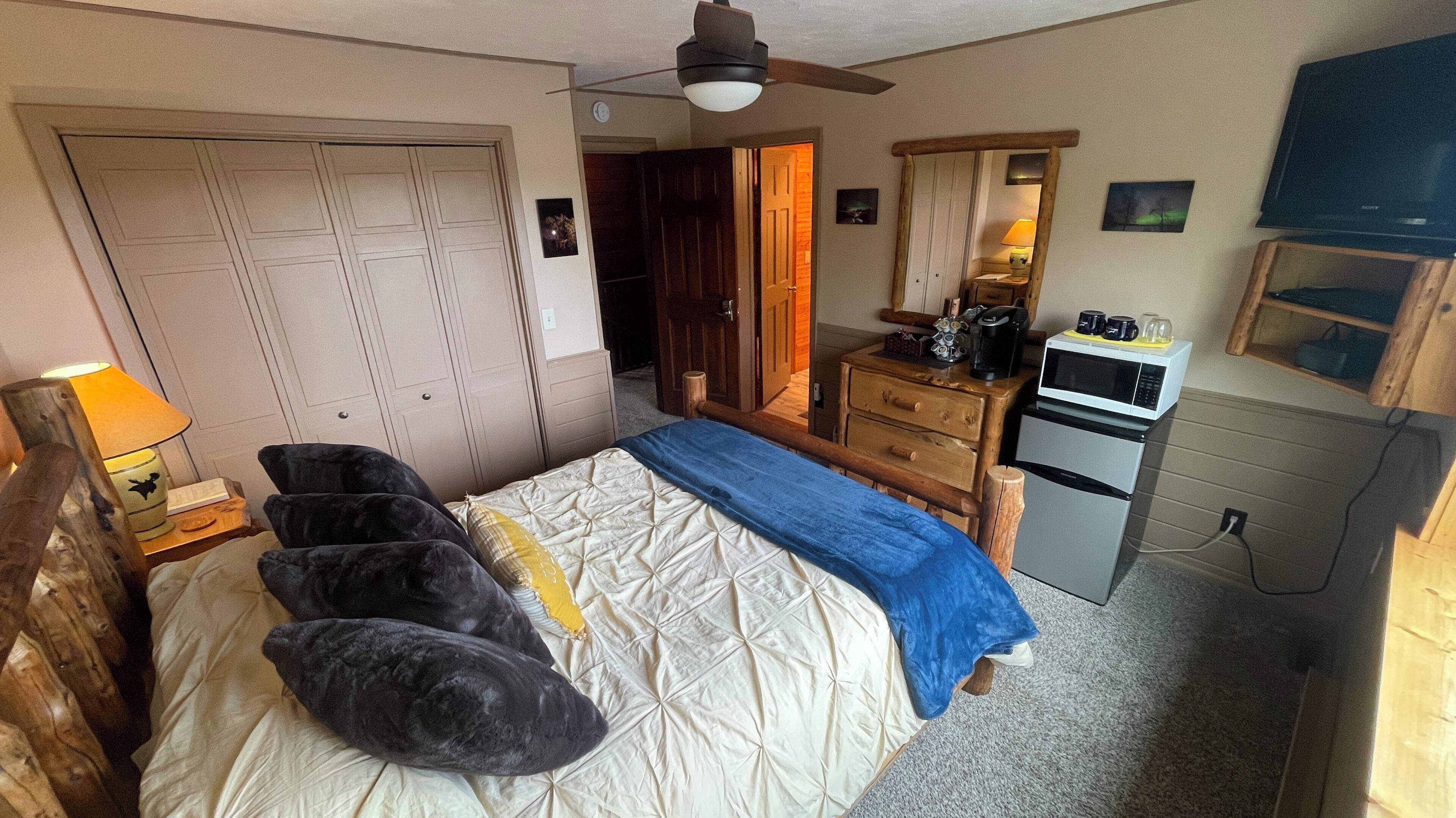 Quarto com cama, penteadeira, micro-ondas e ventilador de teto.