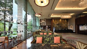 Um lobby de hotel moderno com uma grande área de estar, uma recepção e vista para o exterior.