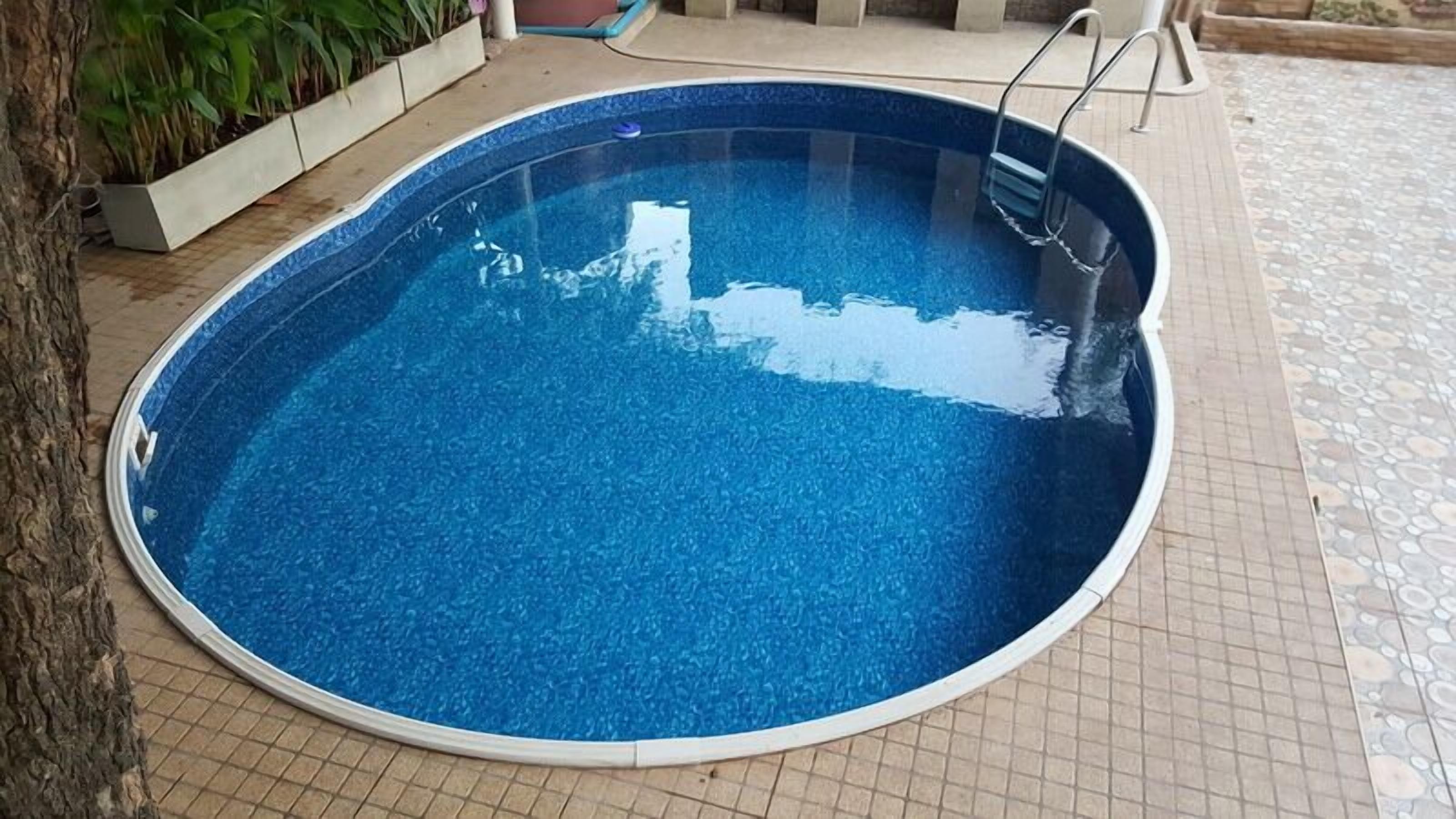 Uma piscina redonda com um deck revestido de azulejos.
