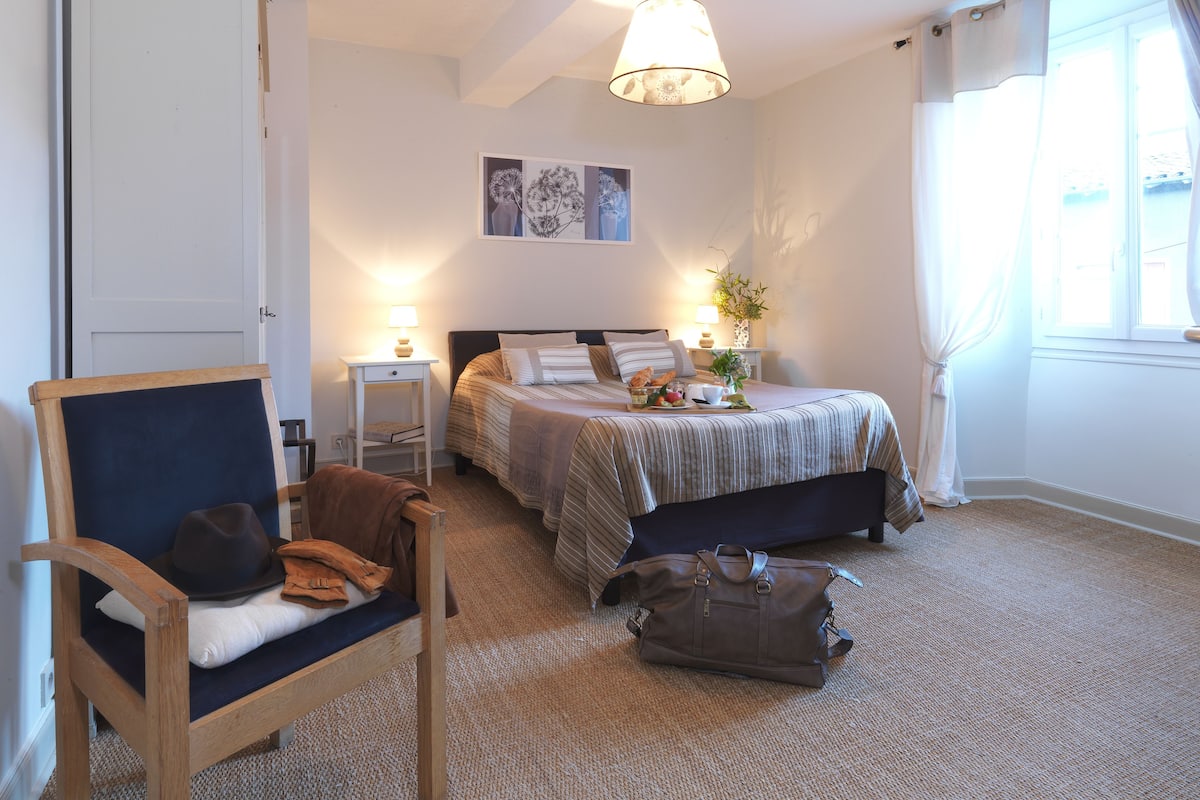Quarto com cama, mesa de cabeceira, abajur e uma cadeira.